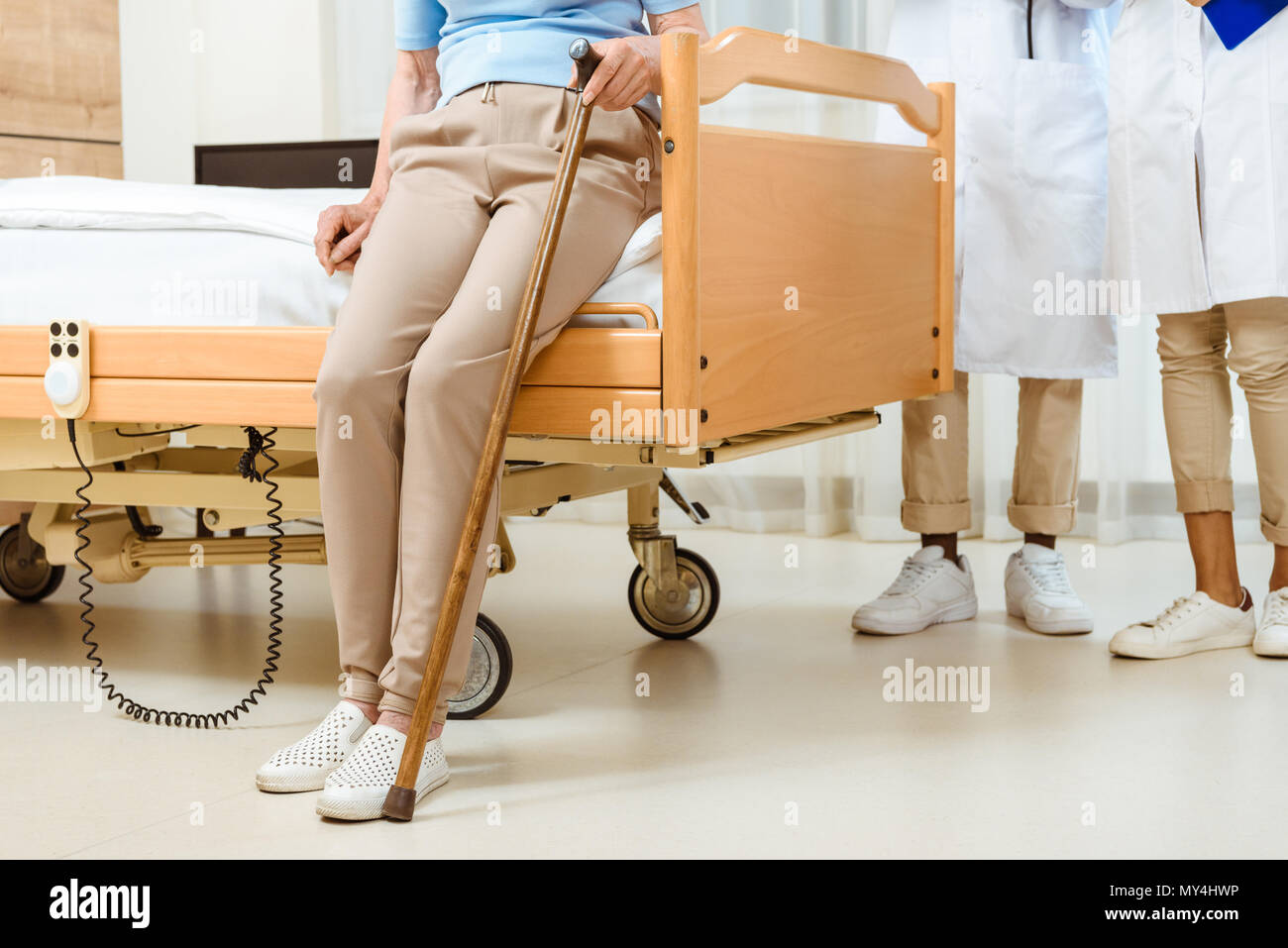 partial view of elderly woman with cane sitting on a hospital bed Stock ...