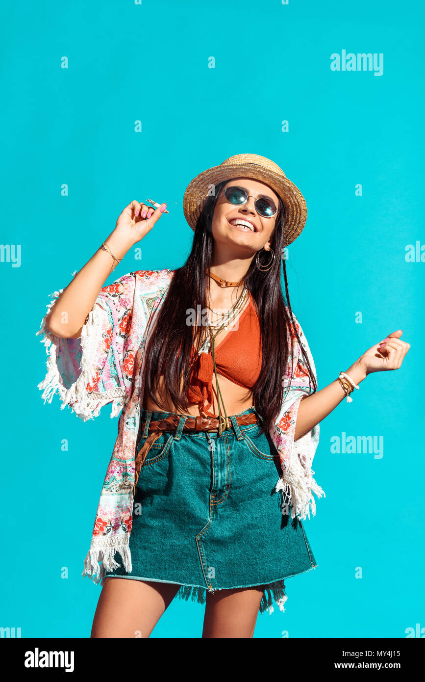 Pretty hippie girl smoking cigarette and dancing isolated on turquoise ...