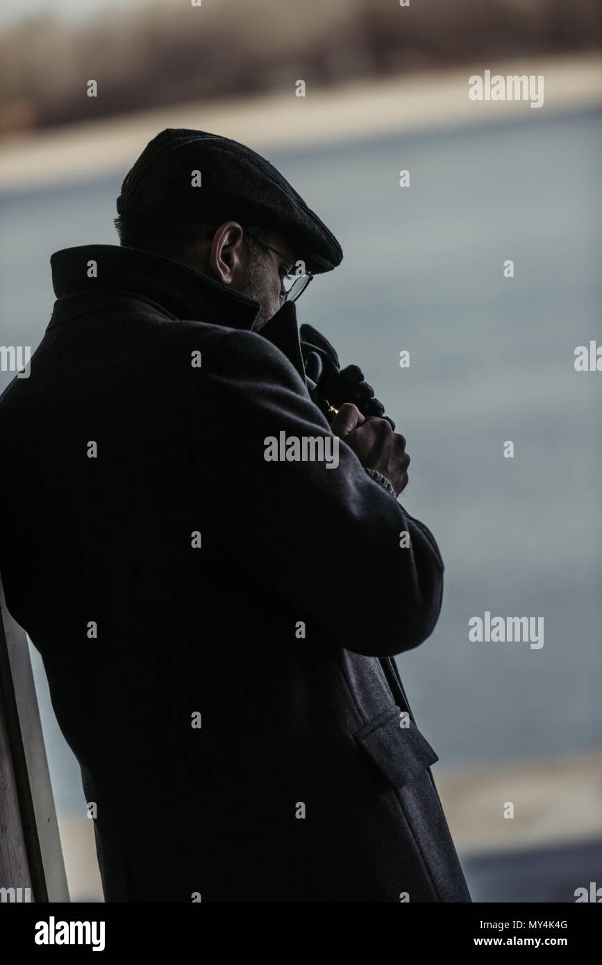 stylish middle aged man smoking while standing in shadow Stock Photo ...