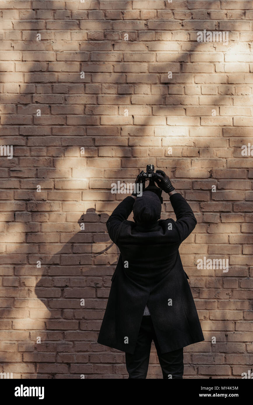 back view of stylish man with camera taking photo of brrick wall Stock ...
