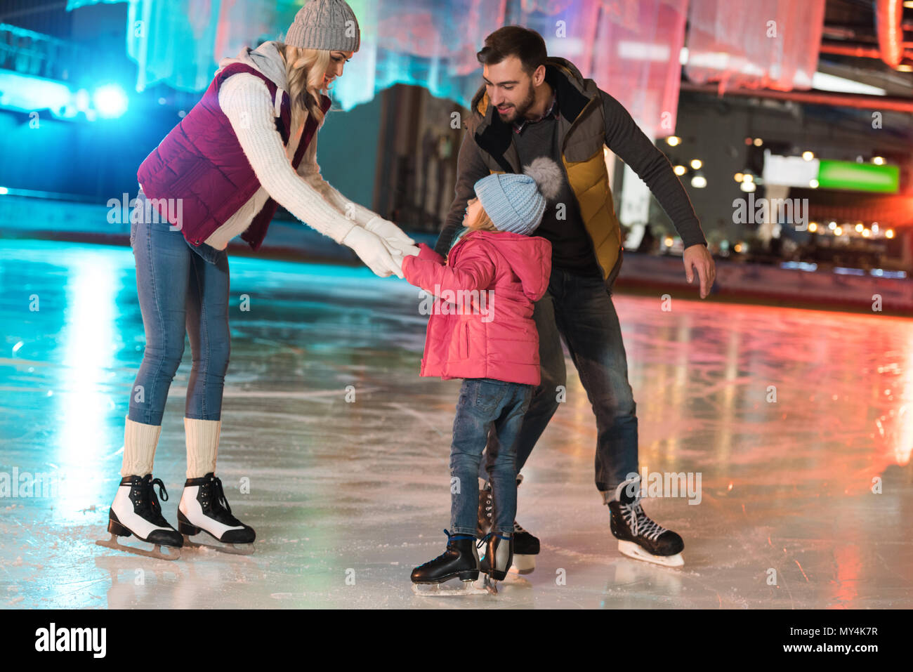 happy parents teaching adorable little daughter skating on rink Stock ...
