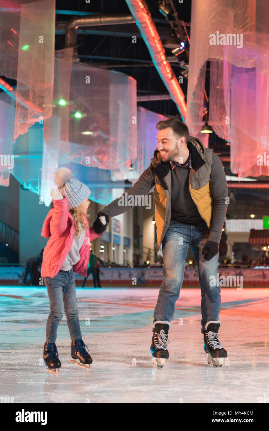 happy father and daughter ice skating together on rink Stock Photo - Alamy