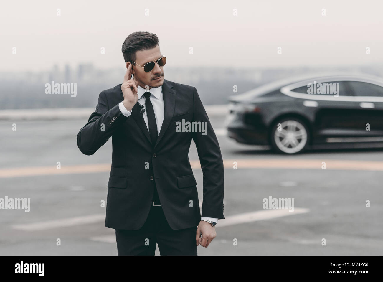 serious bodyguard listening message with security earpiece on helipad ...