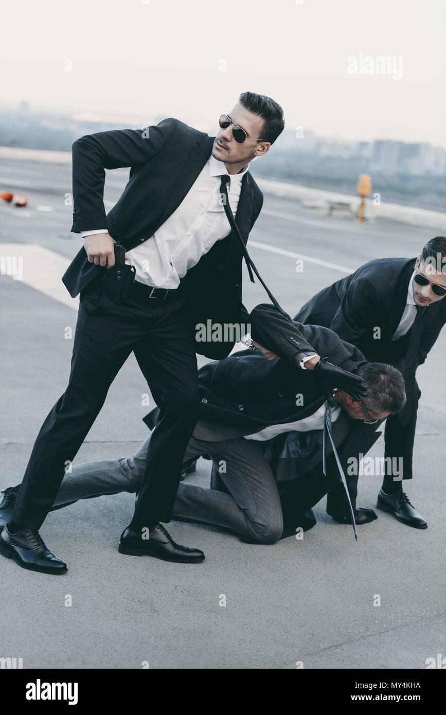 two bodyguards in sunglasses protecting falling businessman Stock Photo ...