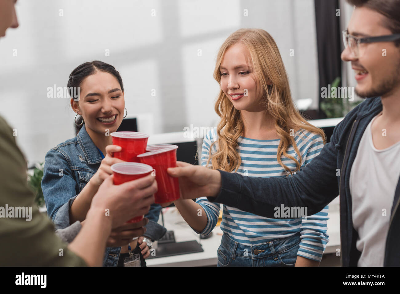 young attractive people clinking cups at modern office Stock Photo - Alamy