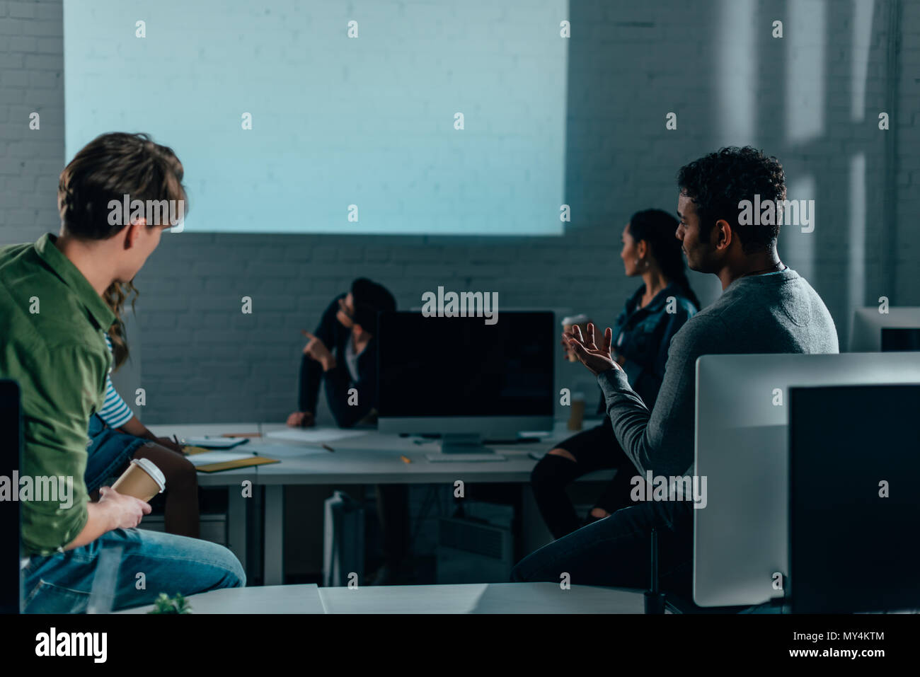 people watching presentation in office at nighttime. blank screen Stock ...