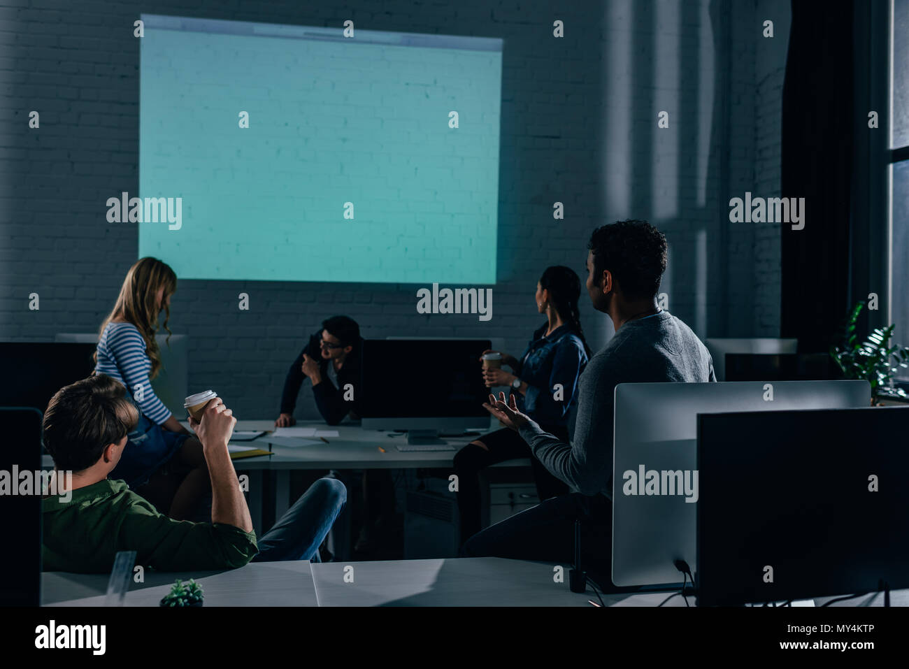 people watching presentation in office at nighttime. blank screen Stock ...