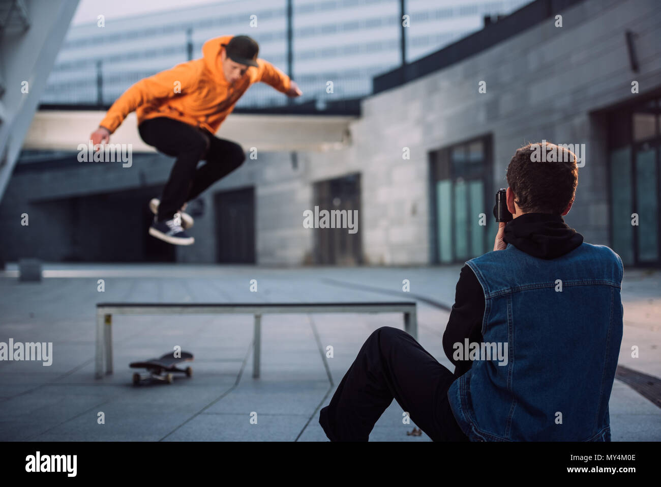 man taking photo of skateboarder jumping over bench Stock Photo - Alamy