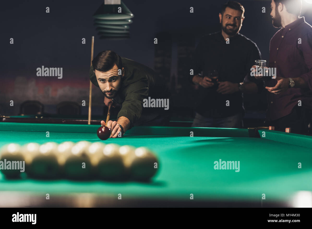 handsome man playing in pool at bar with friends Stock Photo - Alamy