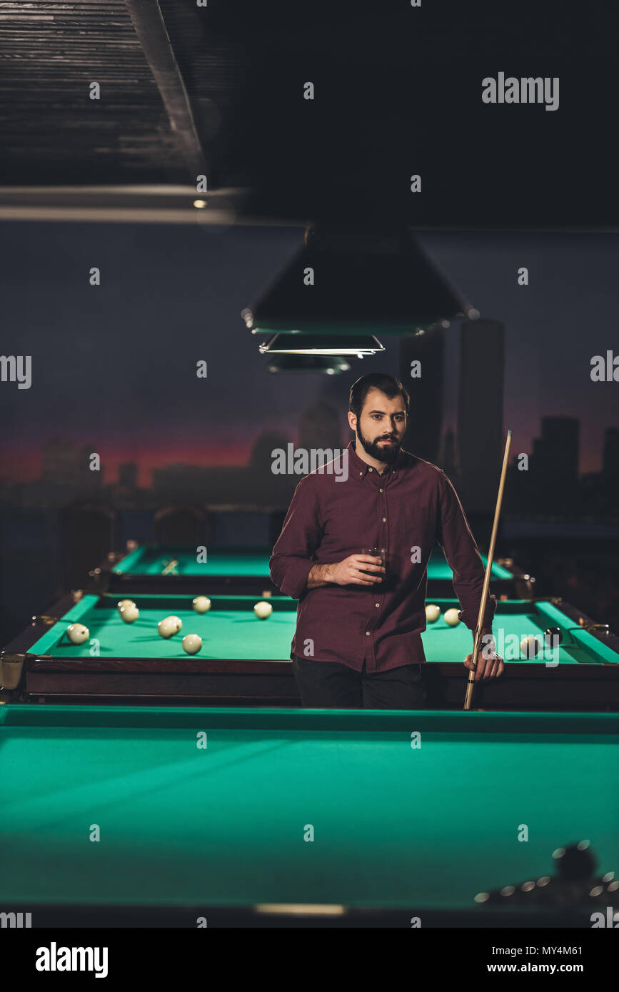 successful handsome man standing beside pool table with drink at bar ...