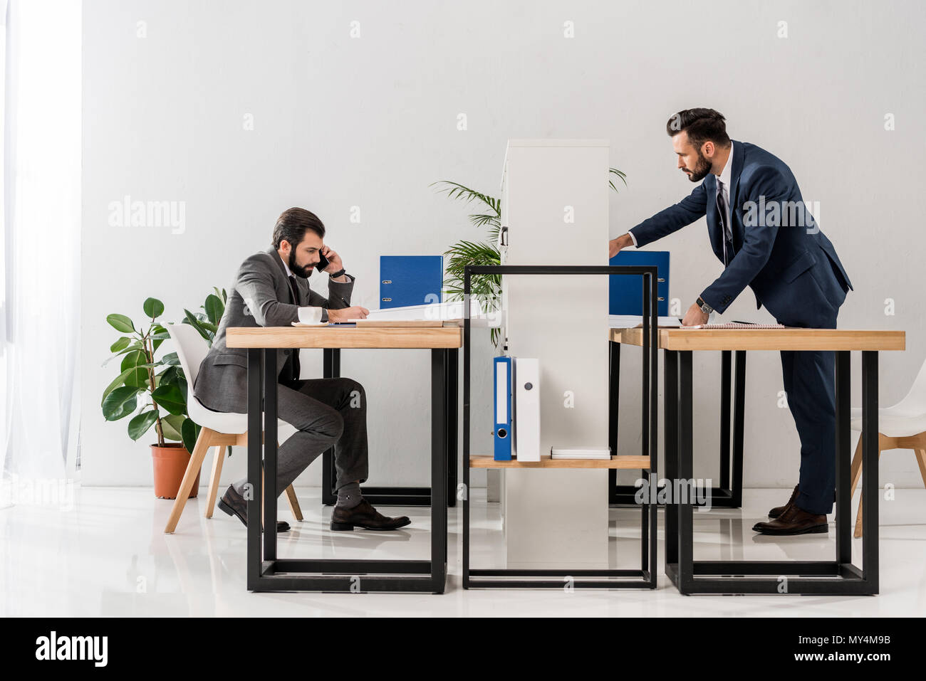 side view of businessmen working at tables in office Stock Photo - Alamy
