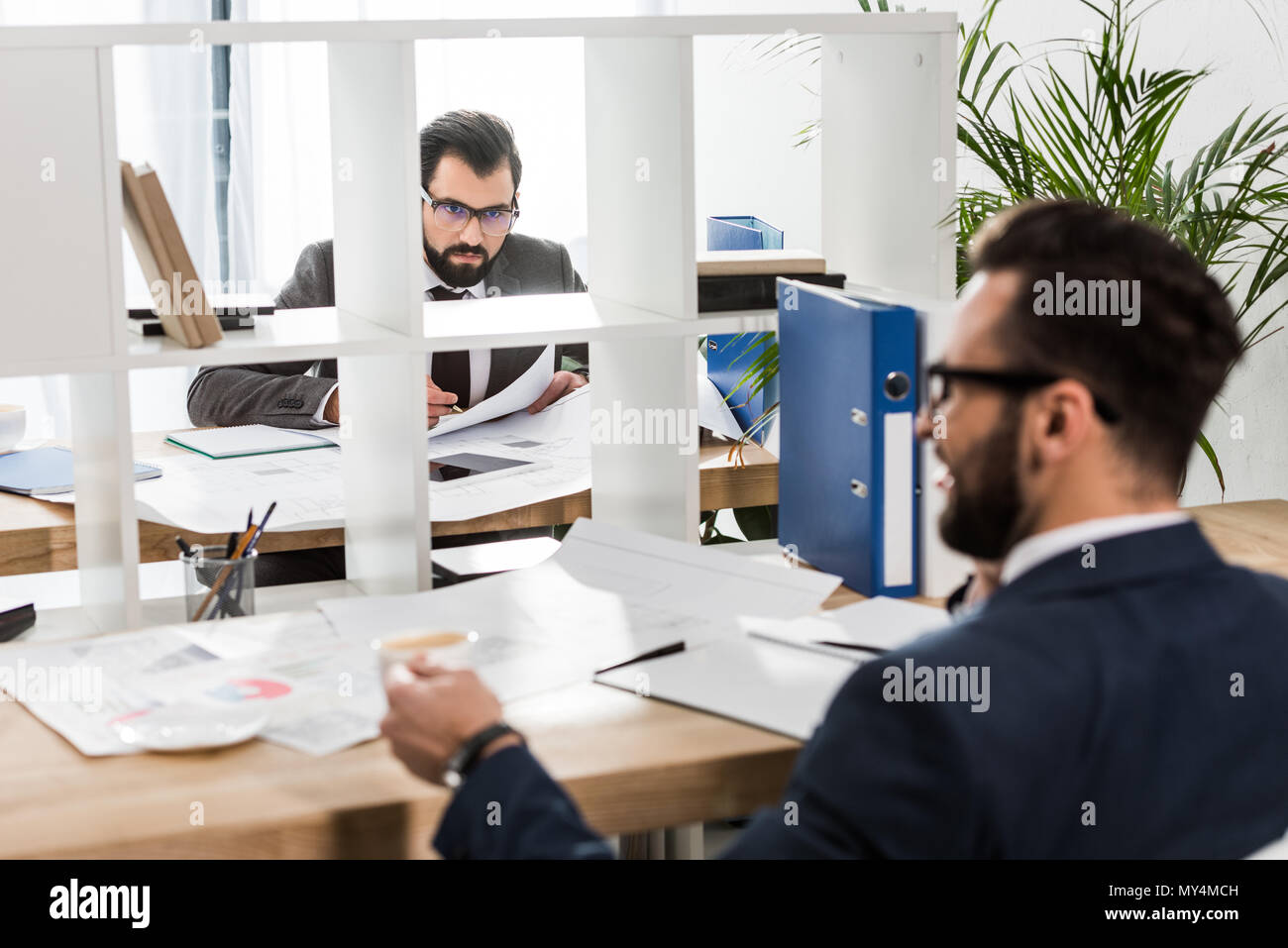 businessmen sitting at working tables with partition between them Stock ...