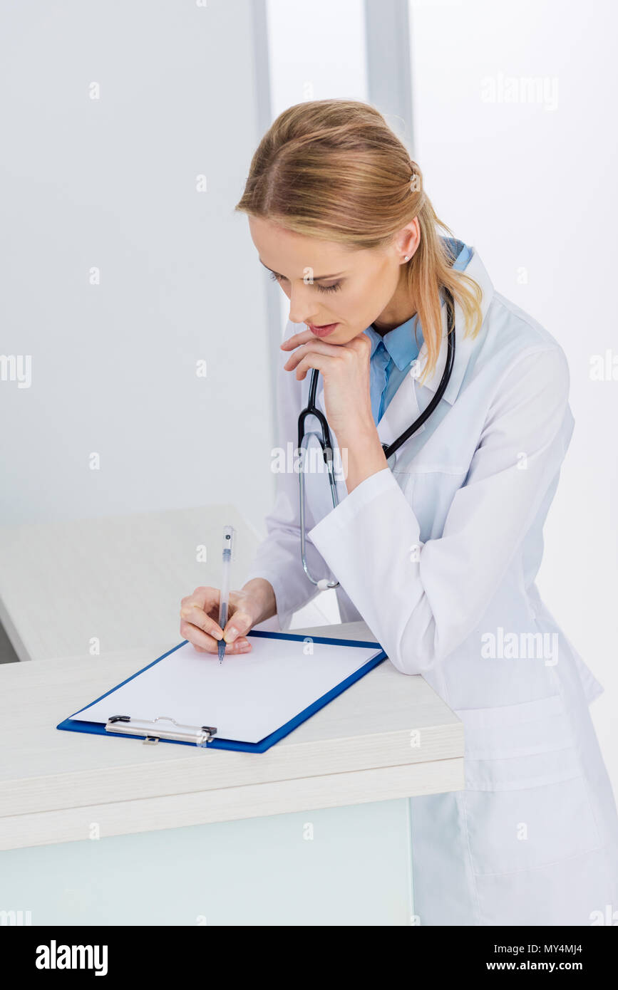 female blonde doctor writing diagnosis in hospital Stock Photo - Alamy