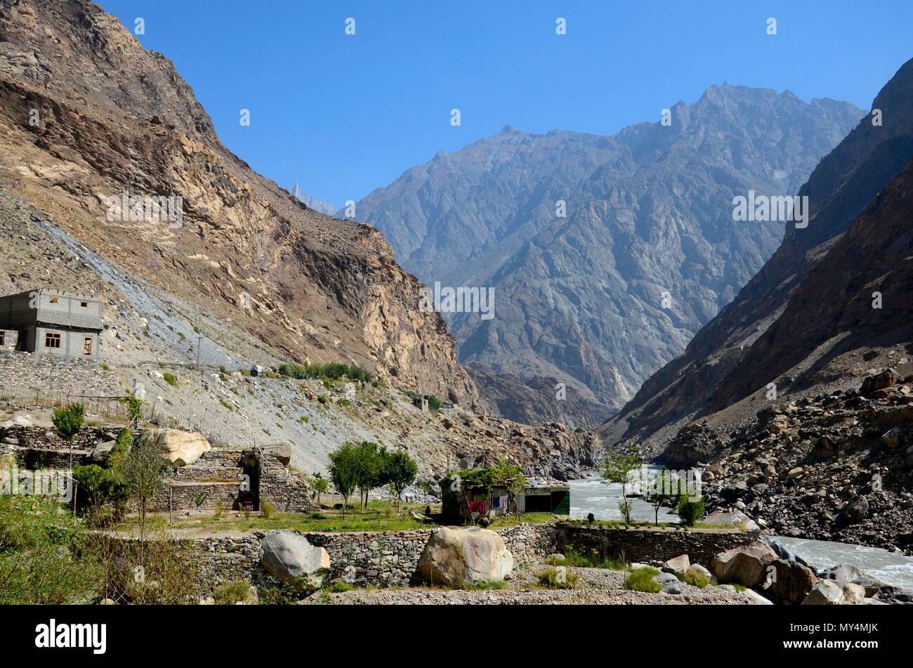 House in valley by riverside and hanging laundry amidst mountains ...