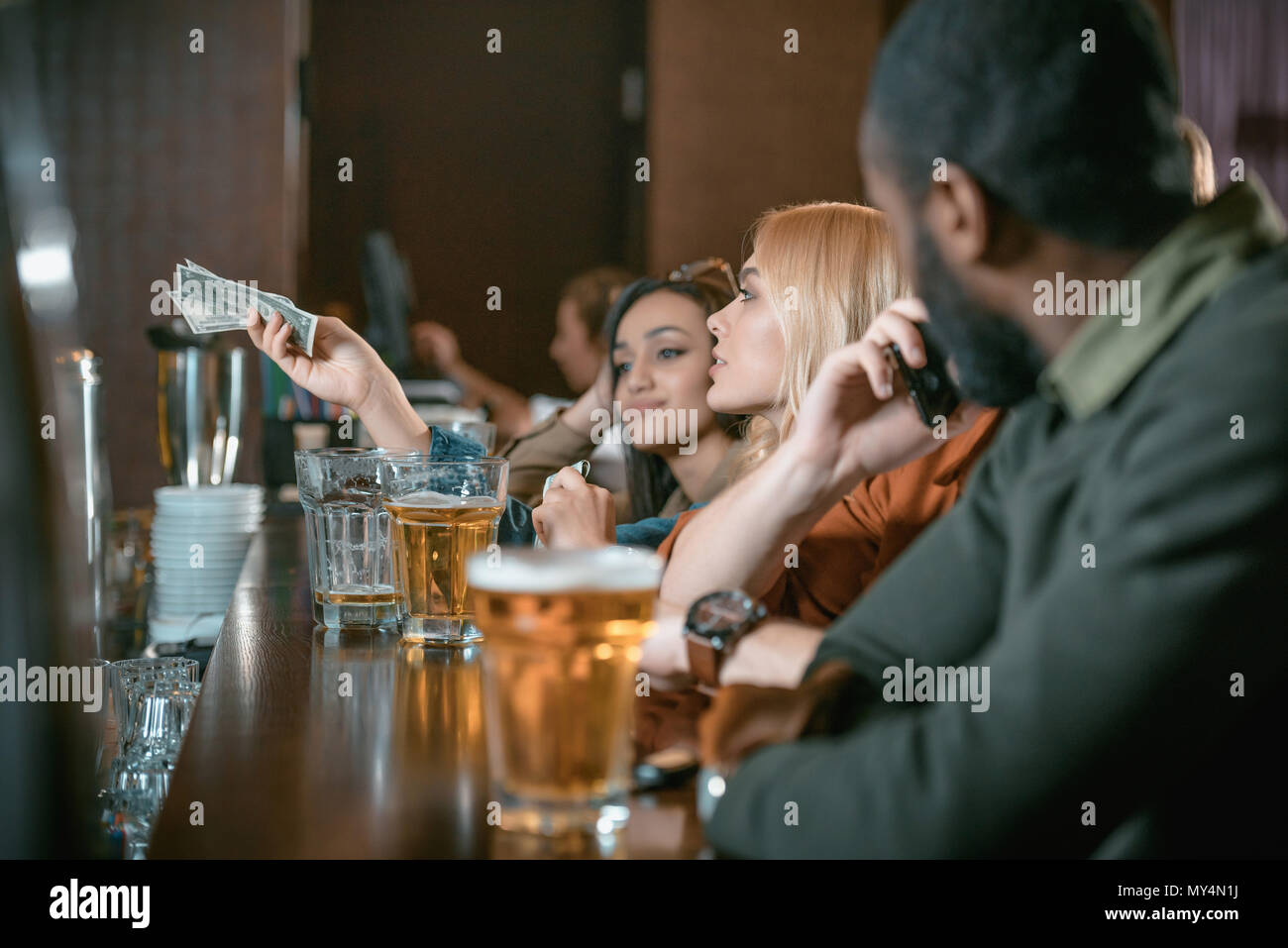 beautiful girl with money paying for drink at bar with friends Stock ...