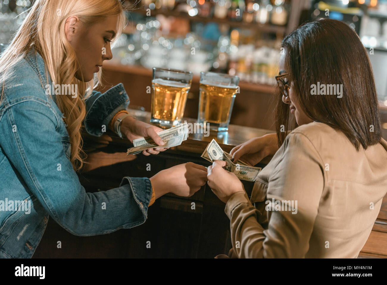 two girls with money paying for drink at bar Stock Photo - Alamy