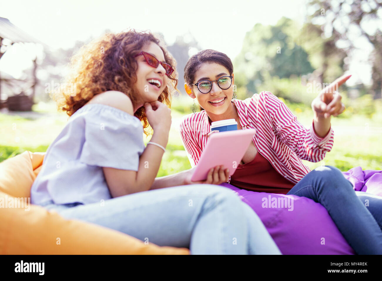 Smiling girl pointing at something while talking Stock Photo - Alamy