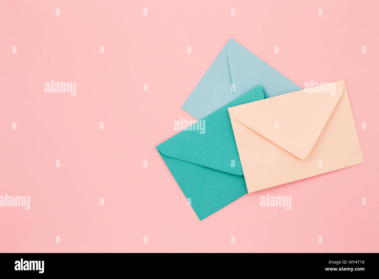 Three colored envelopes on pink background. Minimalist styled ...