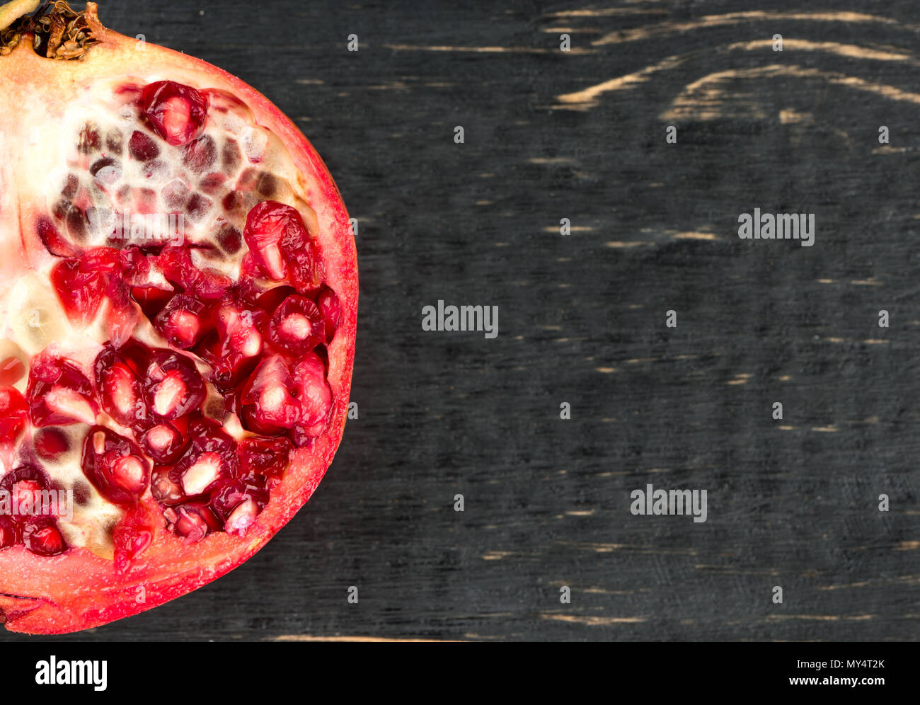 Part of half a pomegranate on a dark table closeup Stock Photo - Alamy
