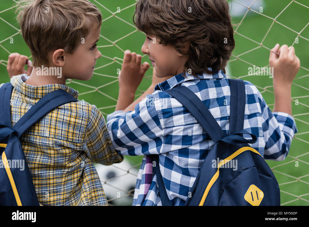 back view of two little schoolboys standing near soccer gate and ...