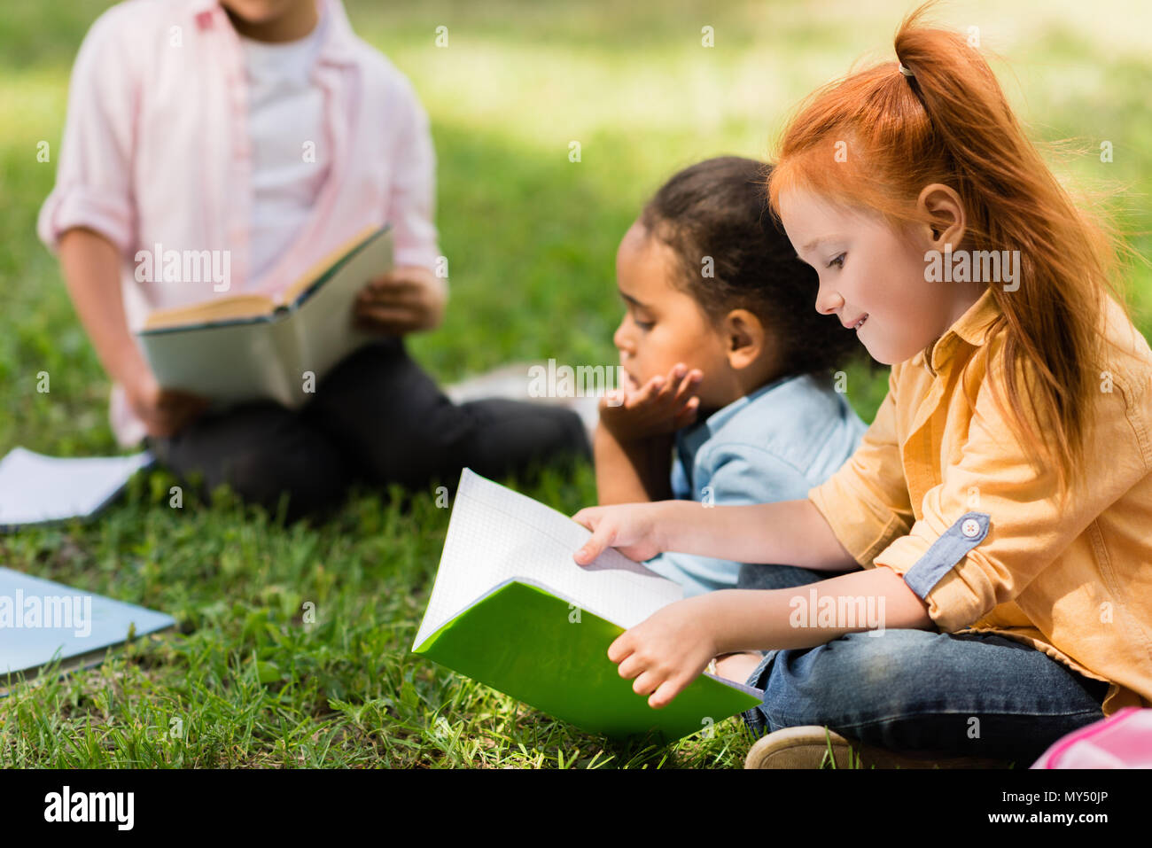 beautiful multiethnic girls reading books together in park Stock Photo ...