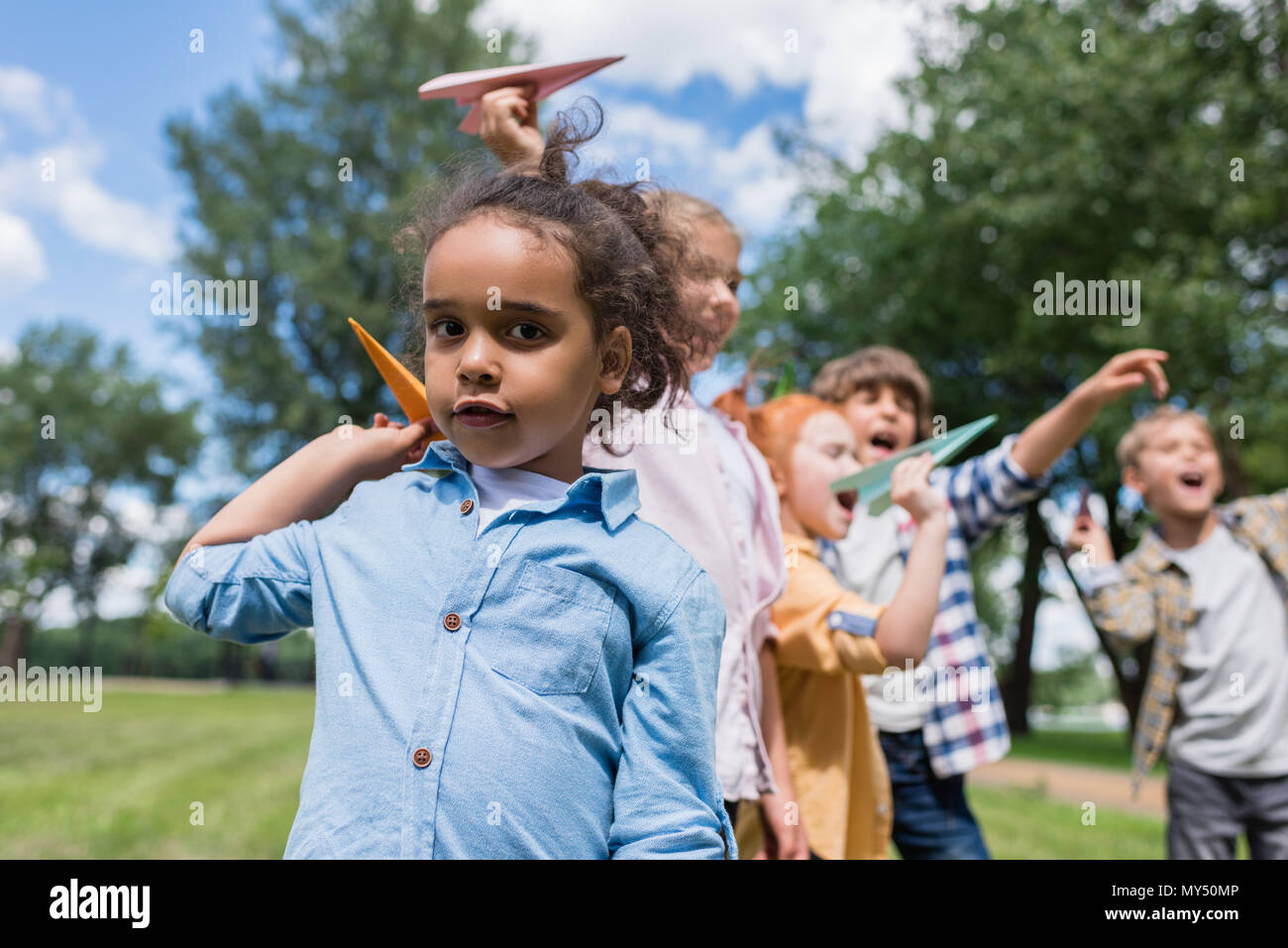 adorable multiethnic kids playing with paper planes in park Stock Photo ...