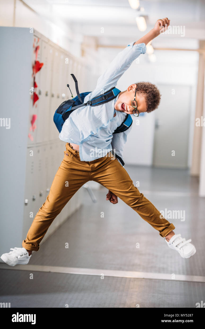 little african american boy jumping in school corridor and celebrating ...