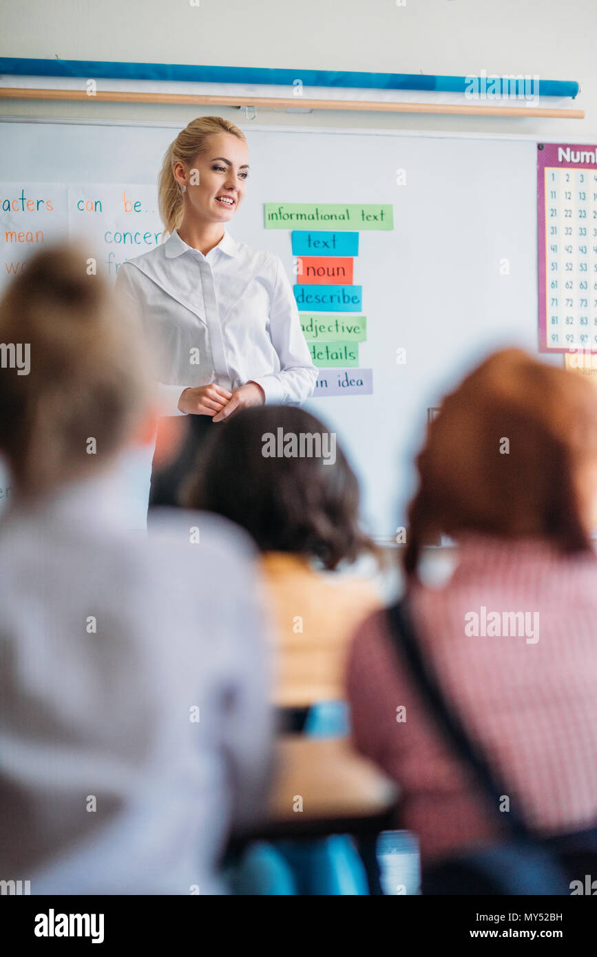 beautiful young teacher in class talking next to whiteboard with ...