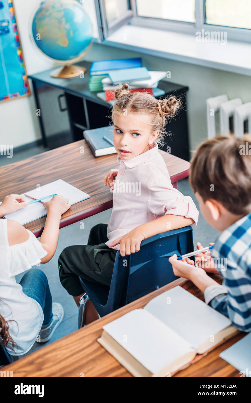 adorable schoolgirl looking back and talking to classmate Stock Photo ...