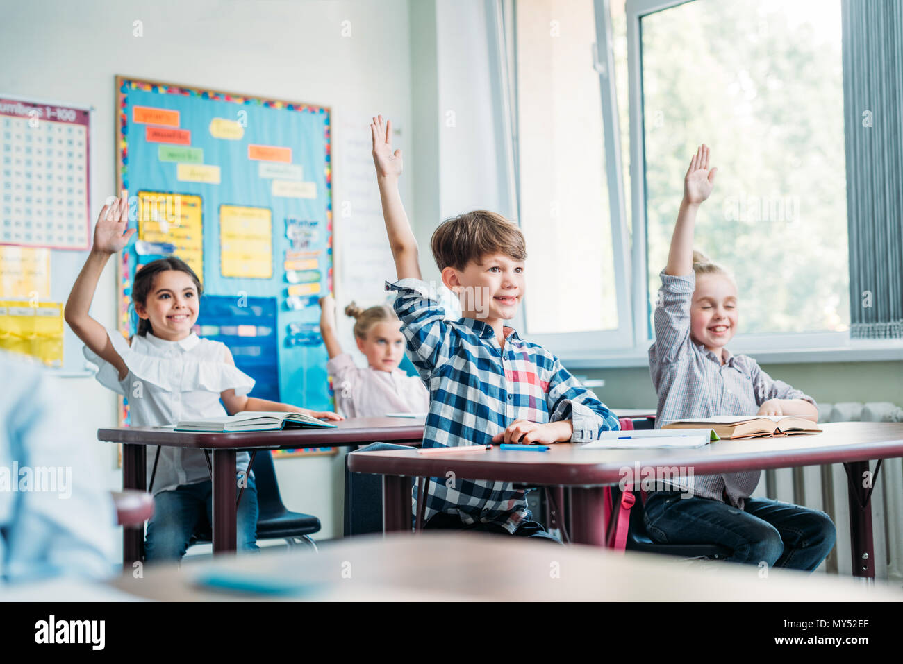 Kids raising hands in class hi-res stock photography and images - Alamy