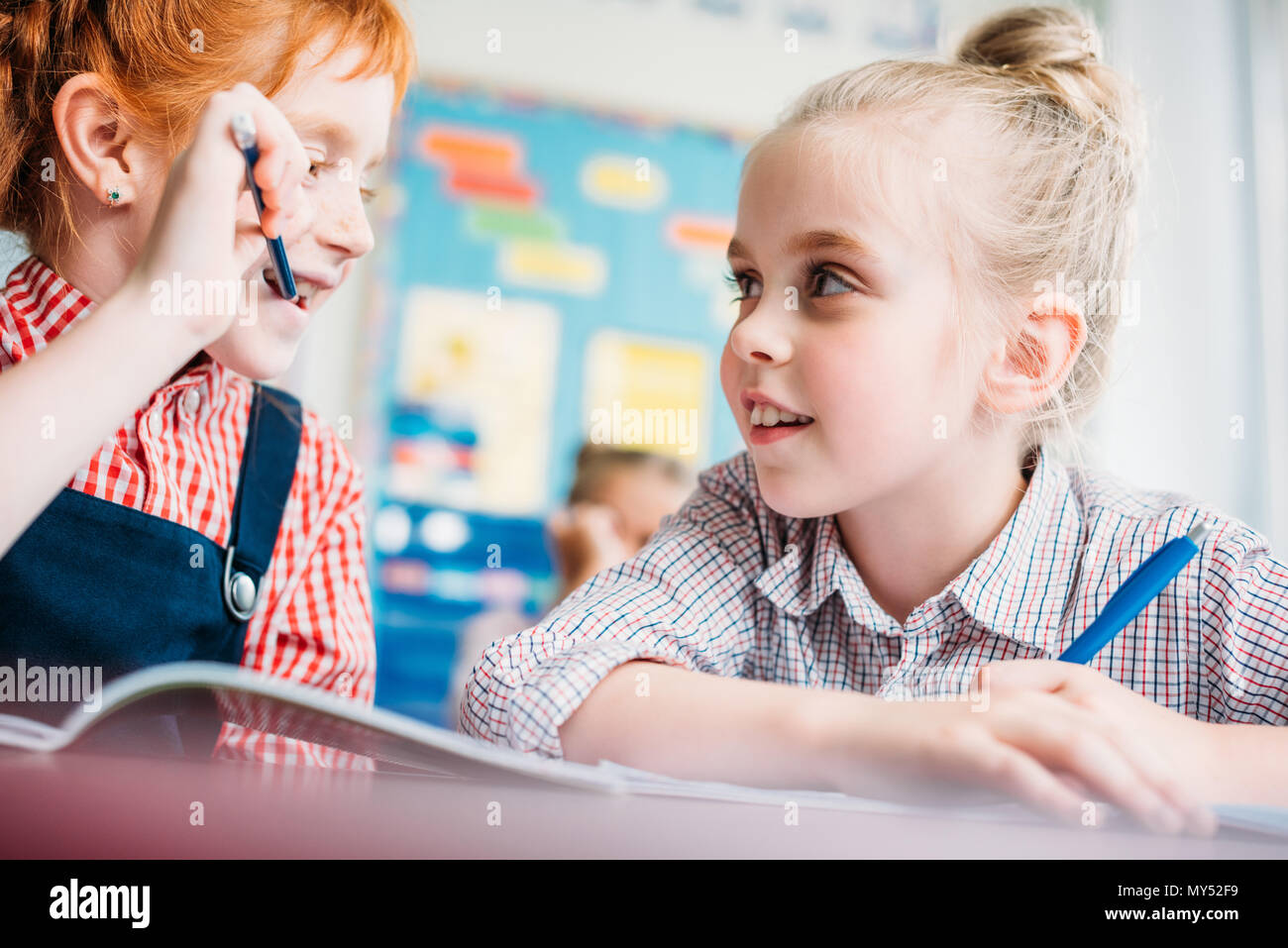 beautiful little girls gossiping in class Stock Photo - Alamy