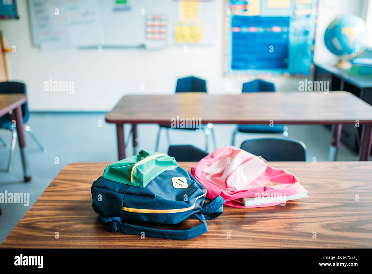 backpacks laying on desk in school classroom Stock Photo - Alamy