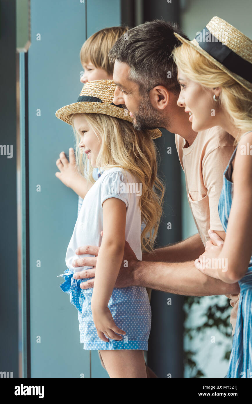 side view of happy family looking out window in airport Stock Photo - Alamy