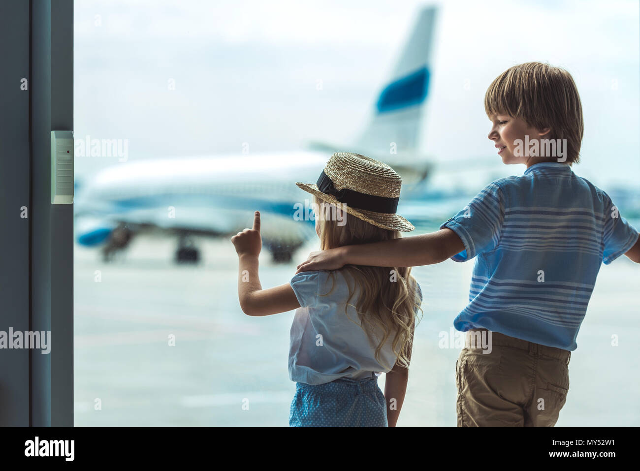 back view of girl pointing away while looking out window together with ...