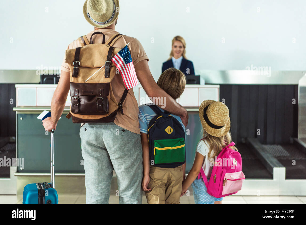 back view of family with backpacks going to check in desk at airport ...