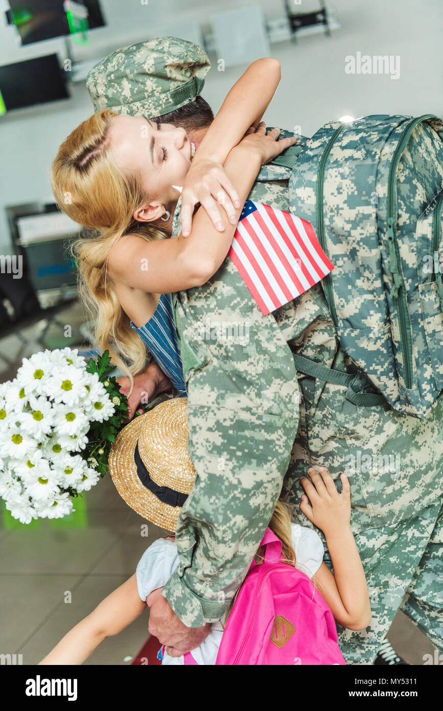 family hugging man in military uniform while meeting at airport Stock ...