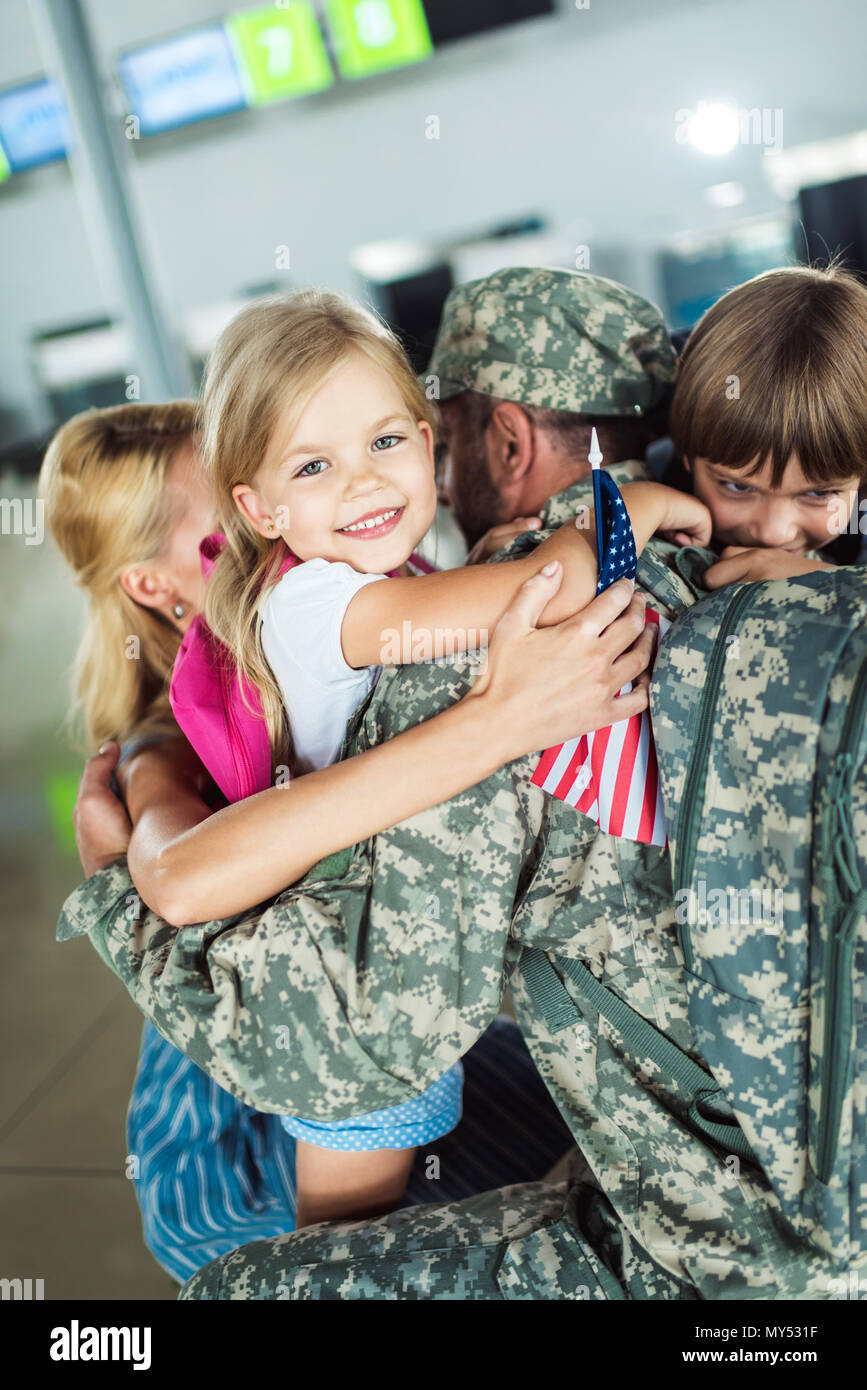 family hugging man in military uniform while meeting at airport Stock ...
