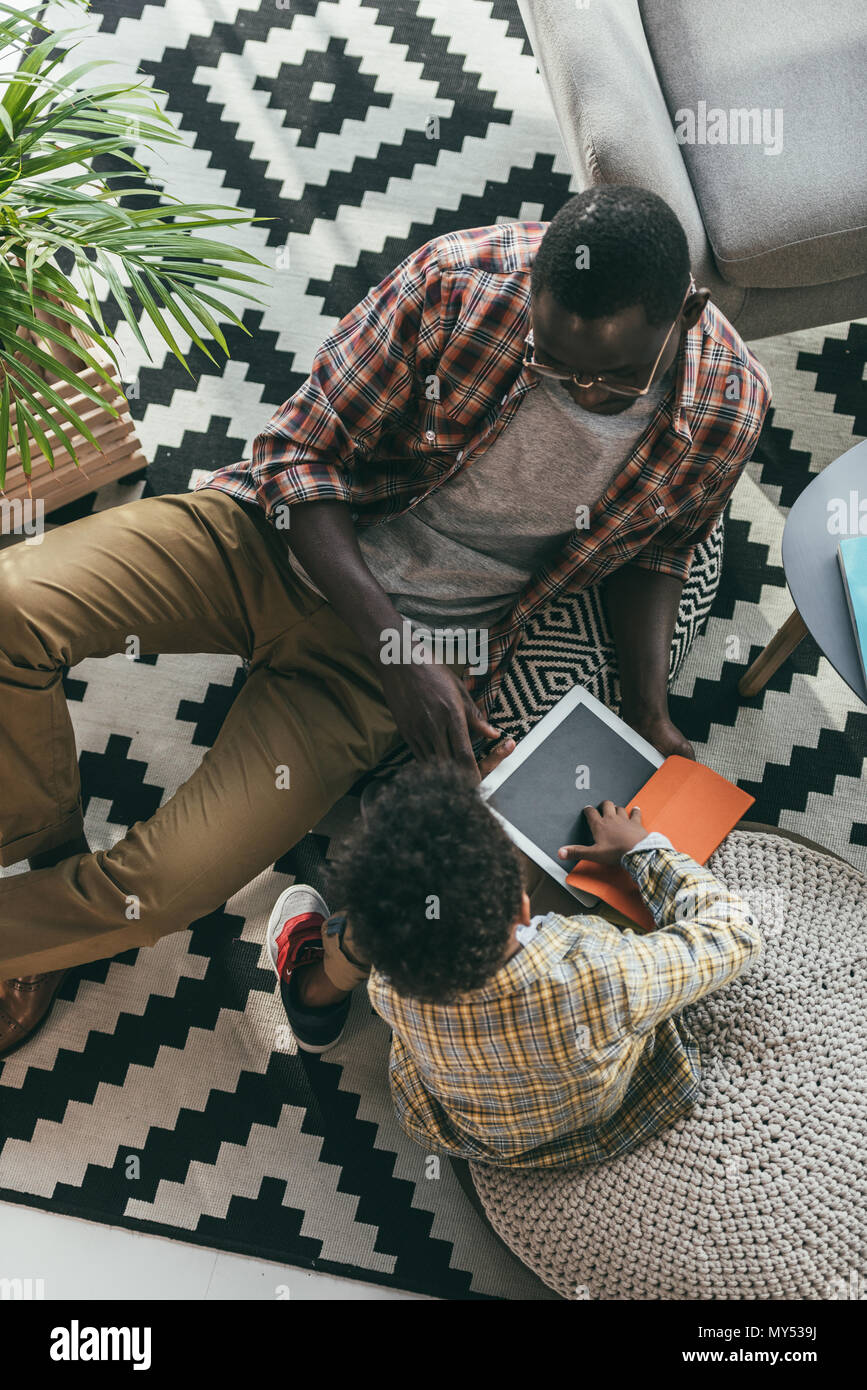 overhead view of african american father and son using digital tablet ...