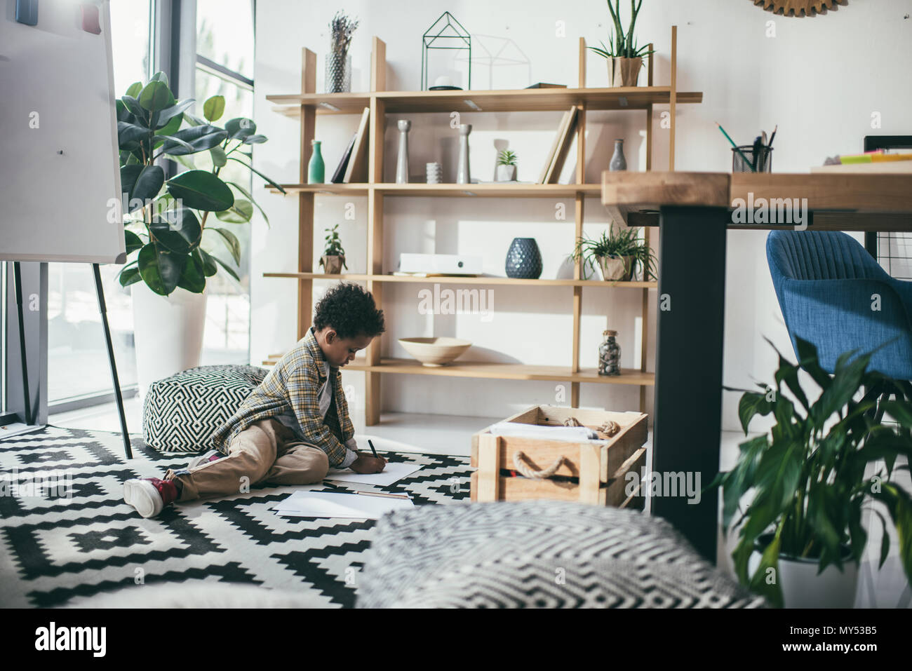 little boy sitting on floor and drawing in modern office Stock Photo ...