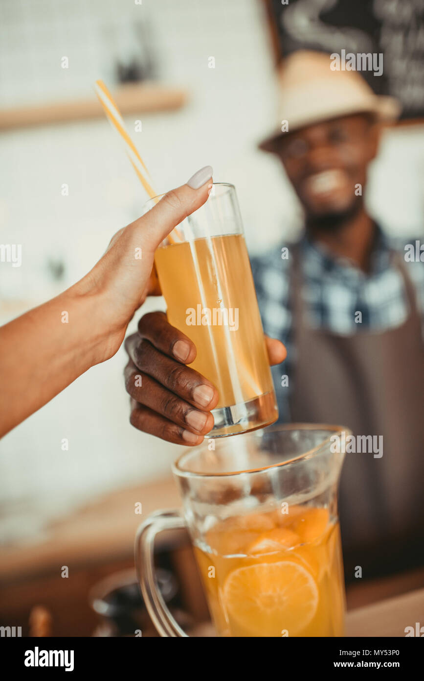 stylish african american bartender giving glass of lemonade to woman in ...