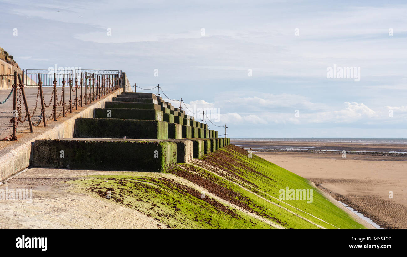 The concrete sea wall at Blackpool Beach is stained green by sea plants ...