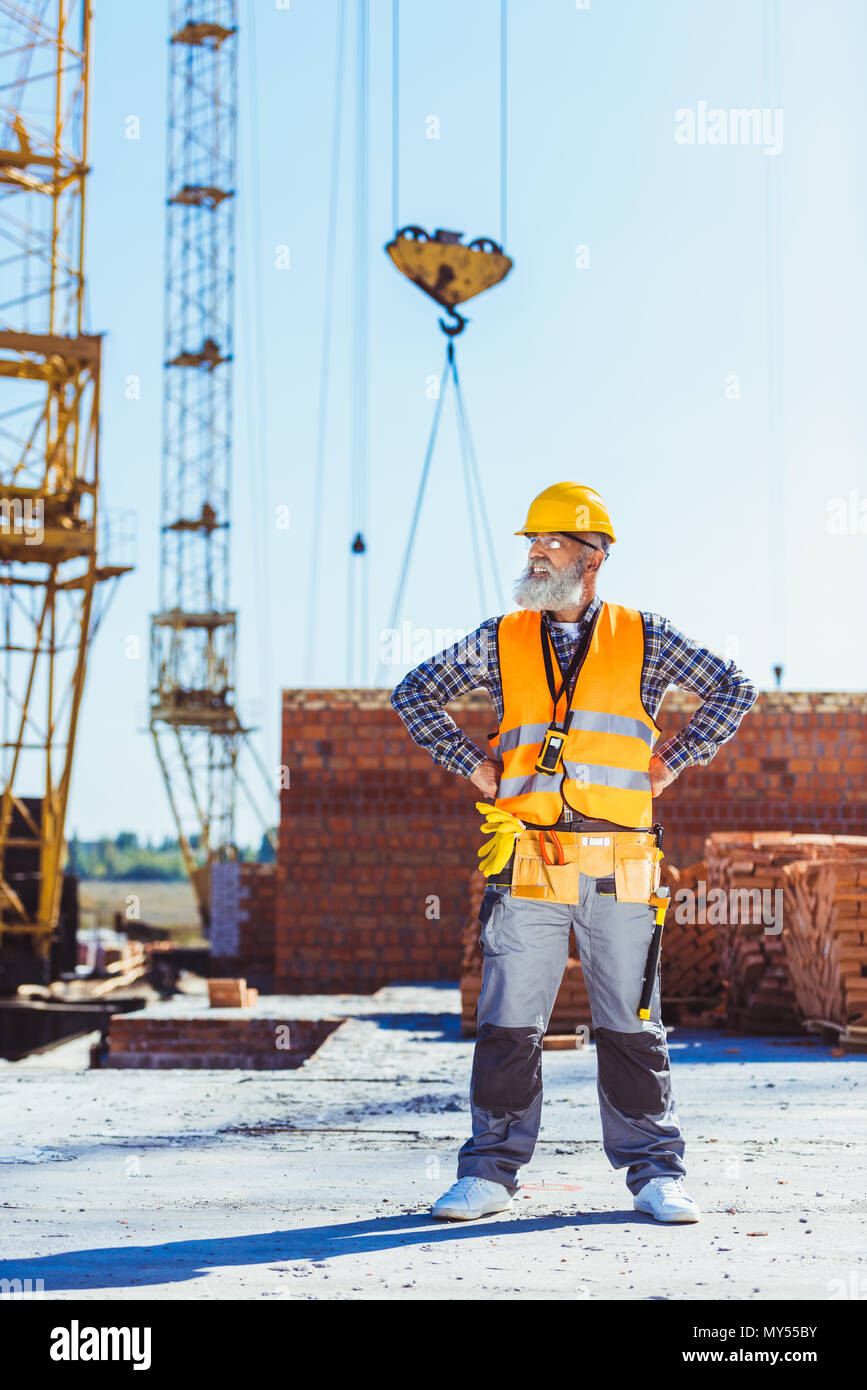 Construction worker in reflective vest and hardhat standing with hands ...