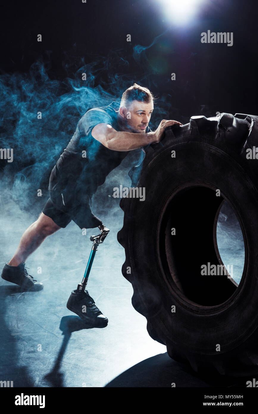 side view of young sportsman with leg prosthesis pulling tire Stock ...