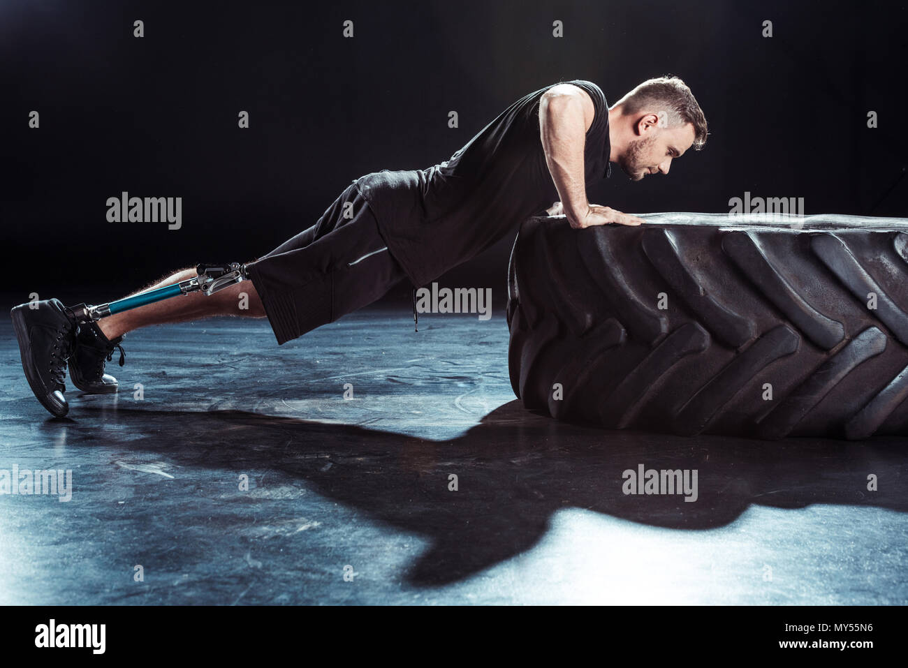 side view of sportsman with leg prosthesis doing push ups on tire Stock ...