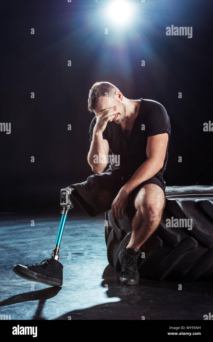 sad sportsman with leg prosthesis sitting on tire after training Stock ...