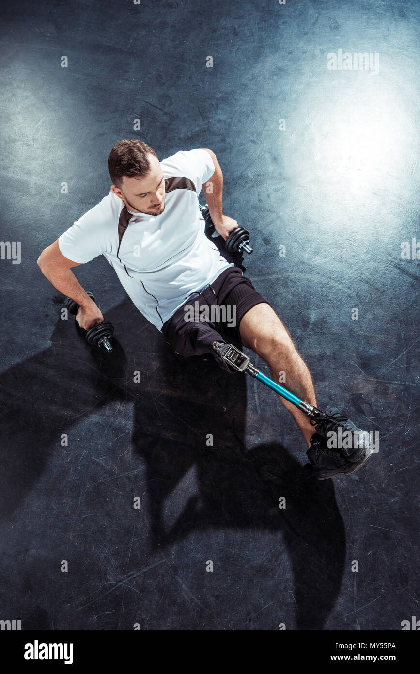overhead view of man with leg prosthesis doing push ups with dumbbells ...