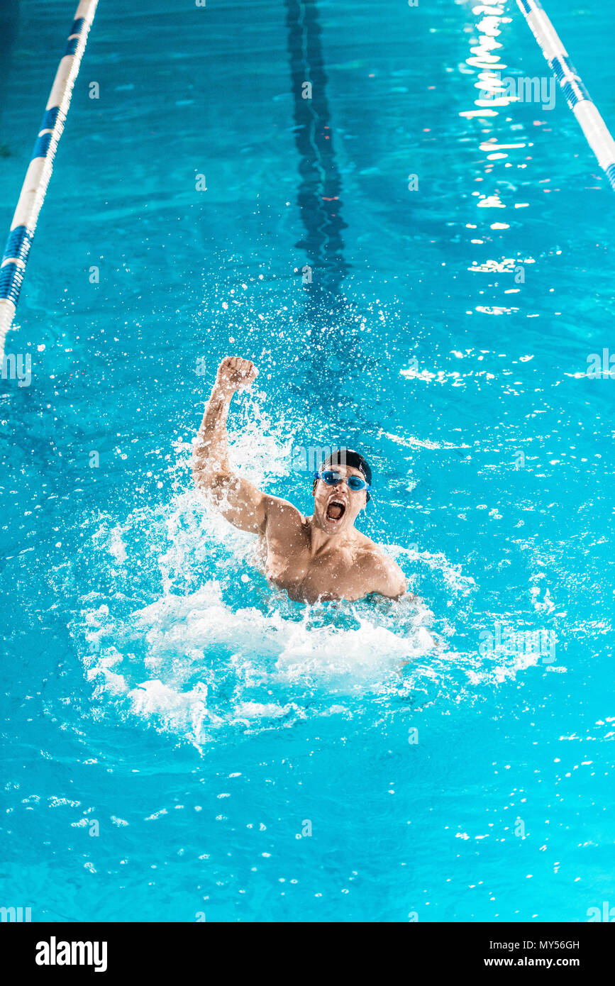 excited swimmer gesturing and making splash in competition swimming ...