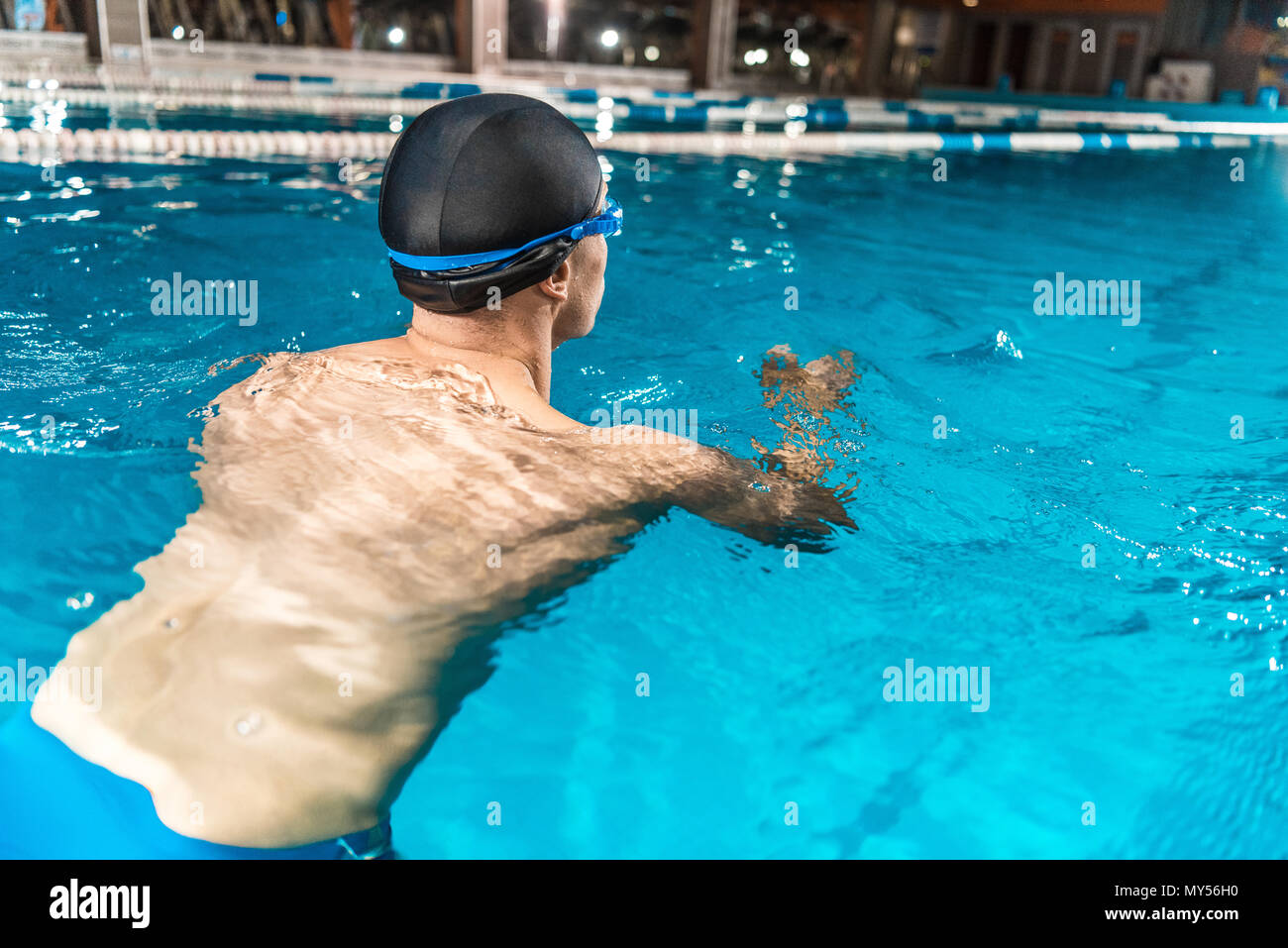 back view of swimmer in swimming cap and goggles swimming in pool Stock ...