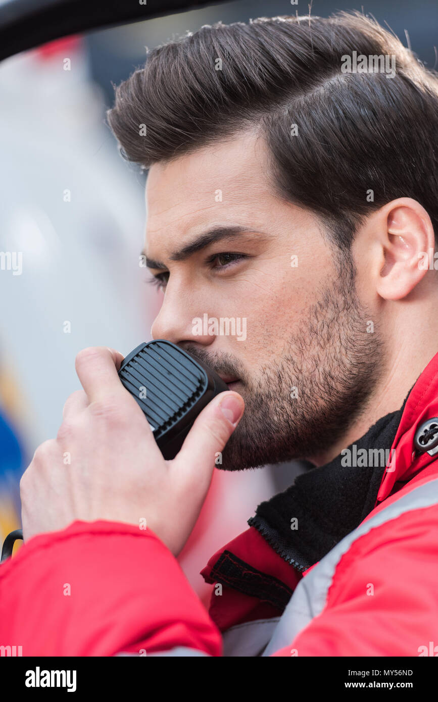 portrait of young handsome male paramedic standing near ambulance and ...