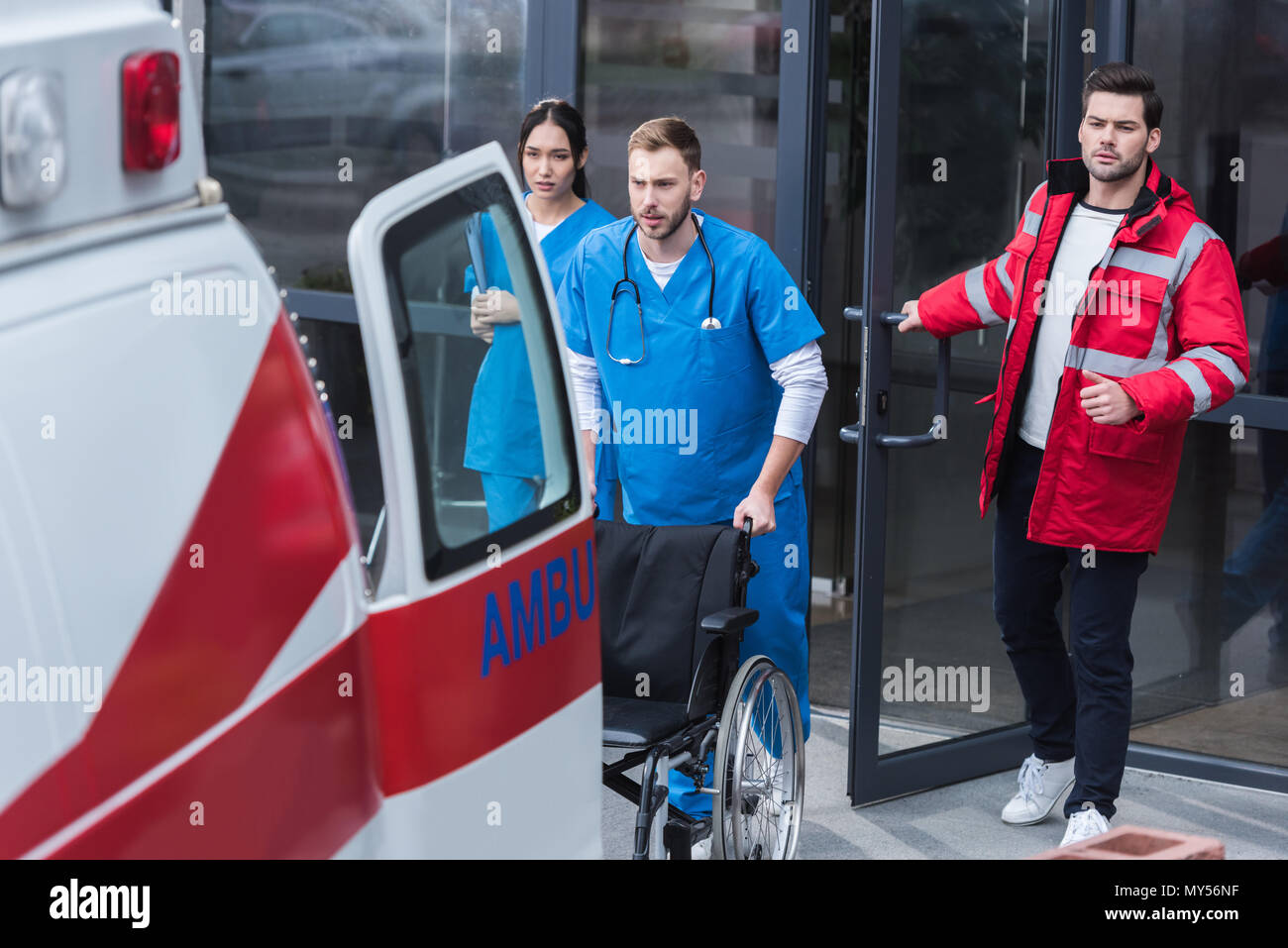 paramedics moving wheelchair from hospital to ambulance Stock Photo - Alamy